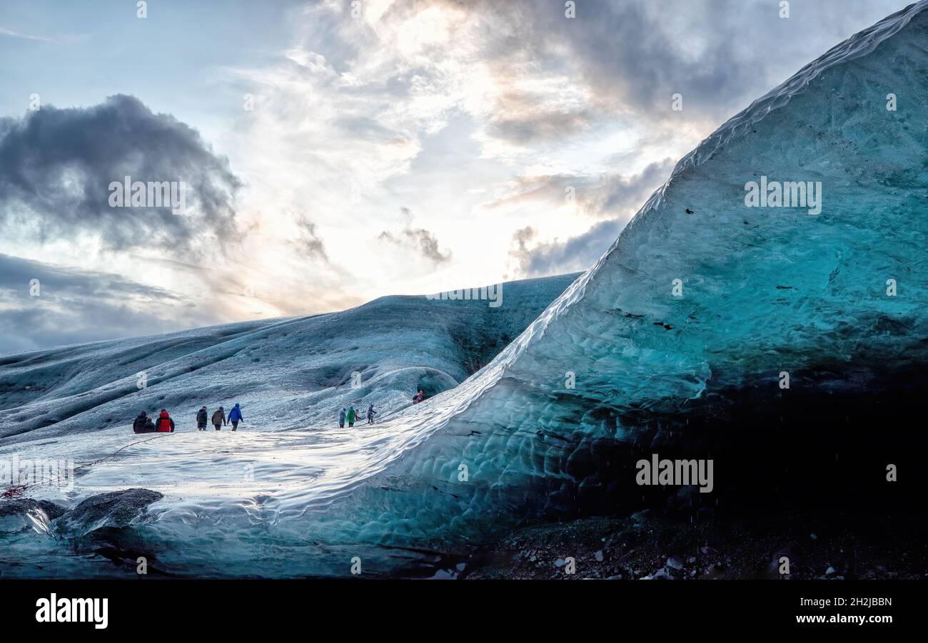 Tourists make their way across a glacier to visit ice caves in Iceland ...