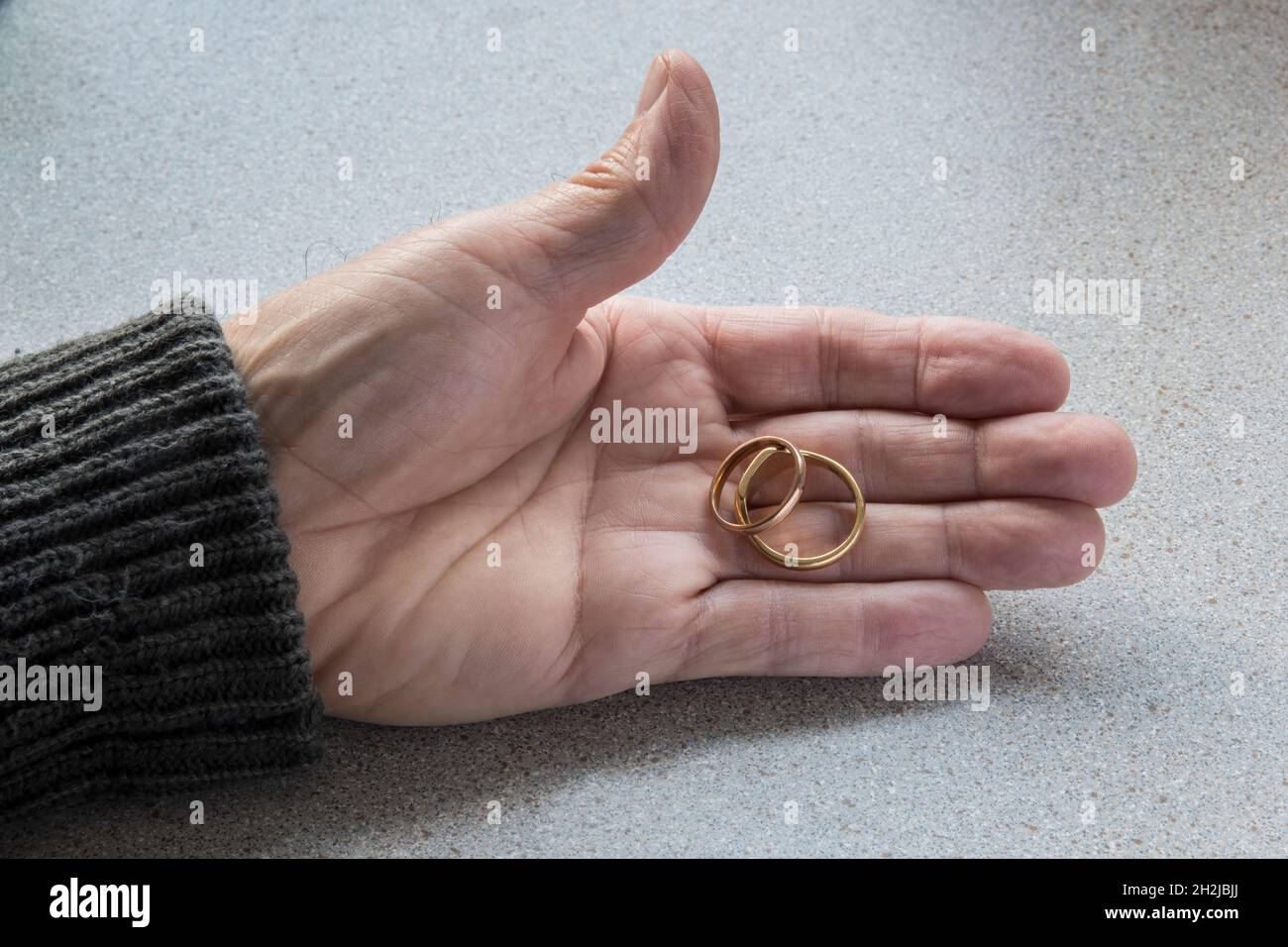 Left alone after death of partner holding rings Stock Photo - Alamy