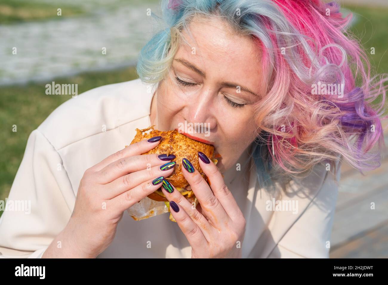 Caucasian woman with curly colored hair eating burger. Bad eating ...