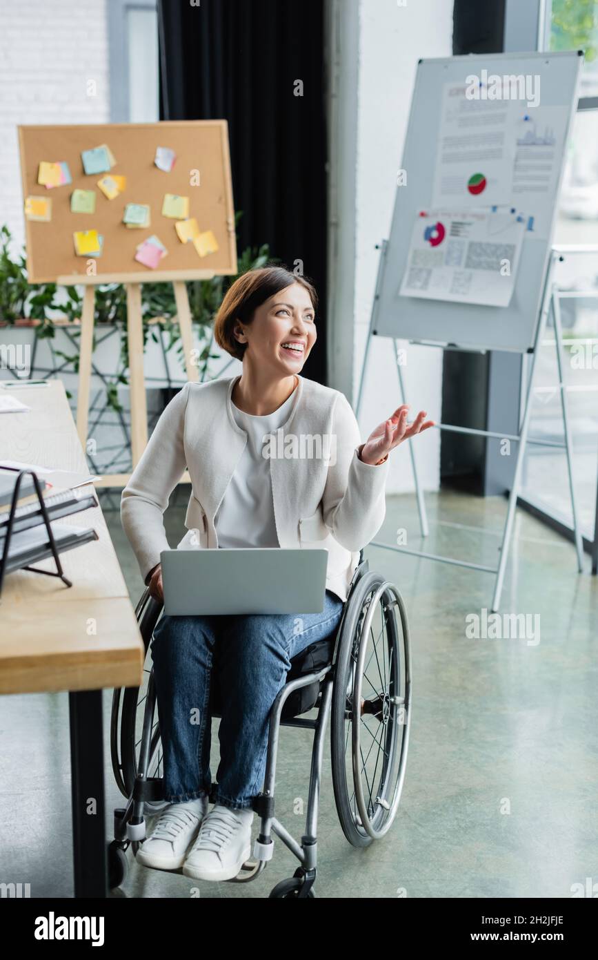 happy businesswoman with disability pointing with hand while working on ...
