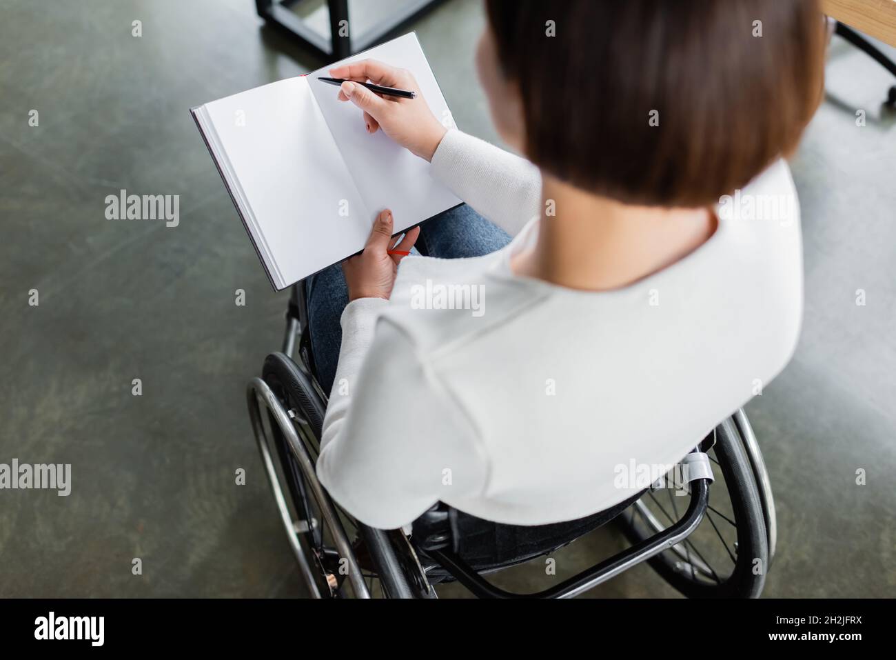 overhead view of businesswoman with physical disability writing in ...