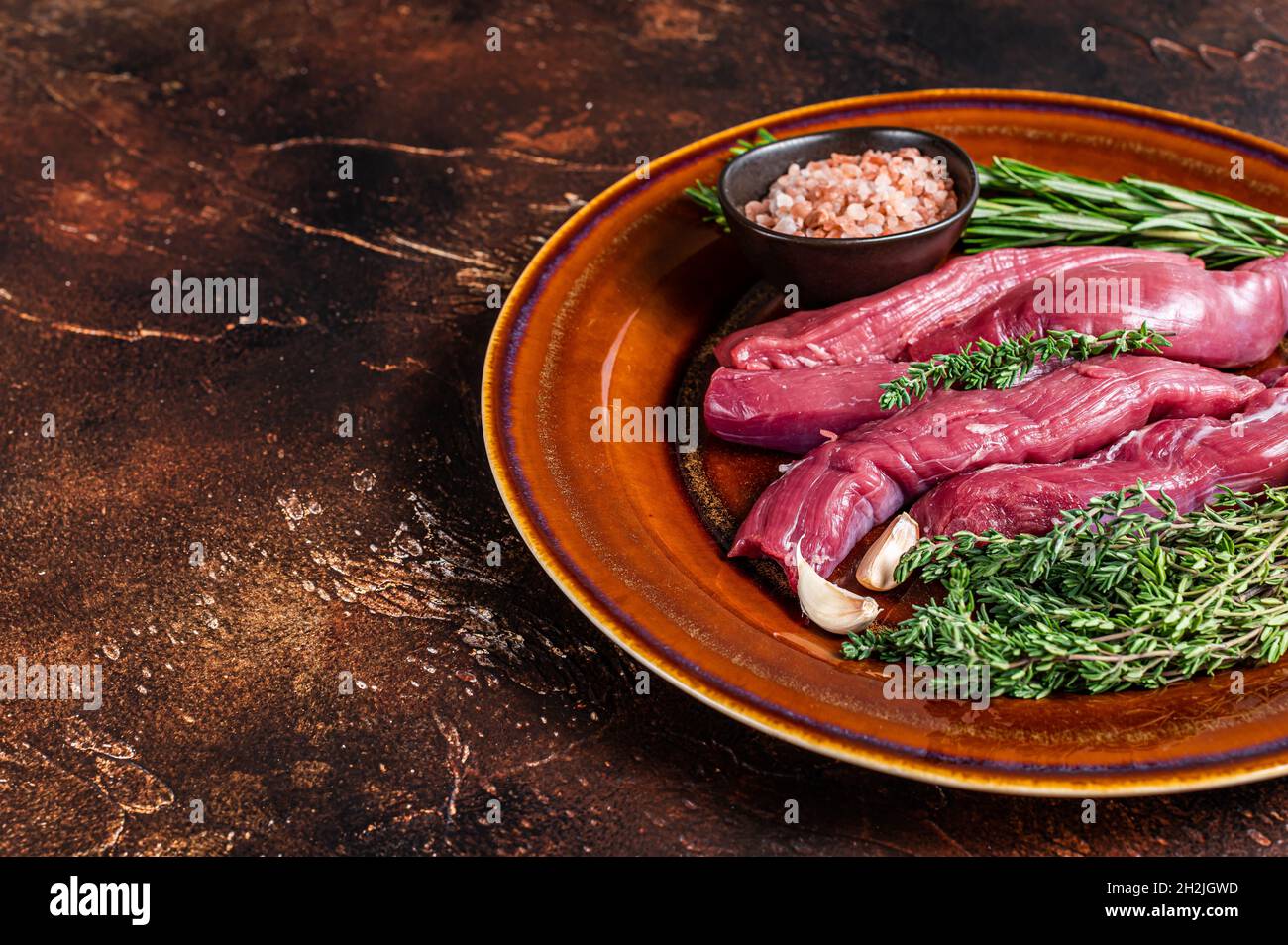 Uncooked Raw lamb tenderloin Fillet Meat in rustic plate with thyme and ...