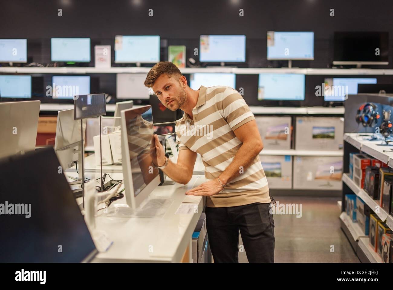 Man in casual clothes looking closely at screen of modern monitor ...