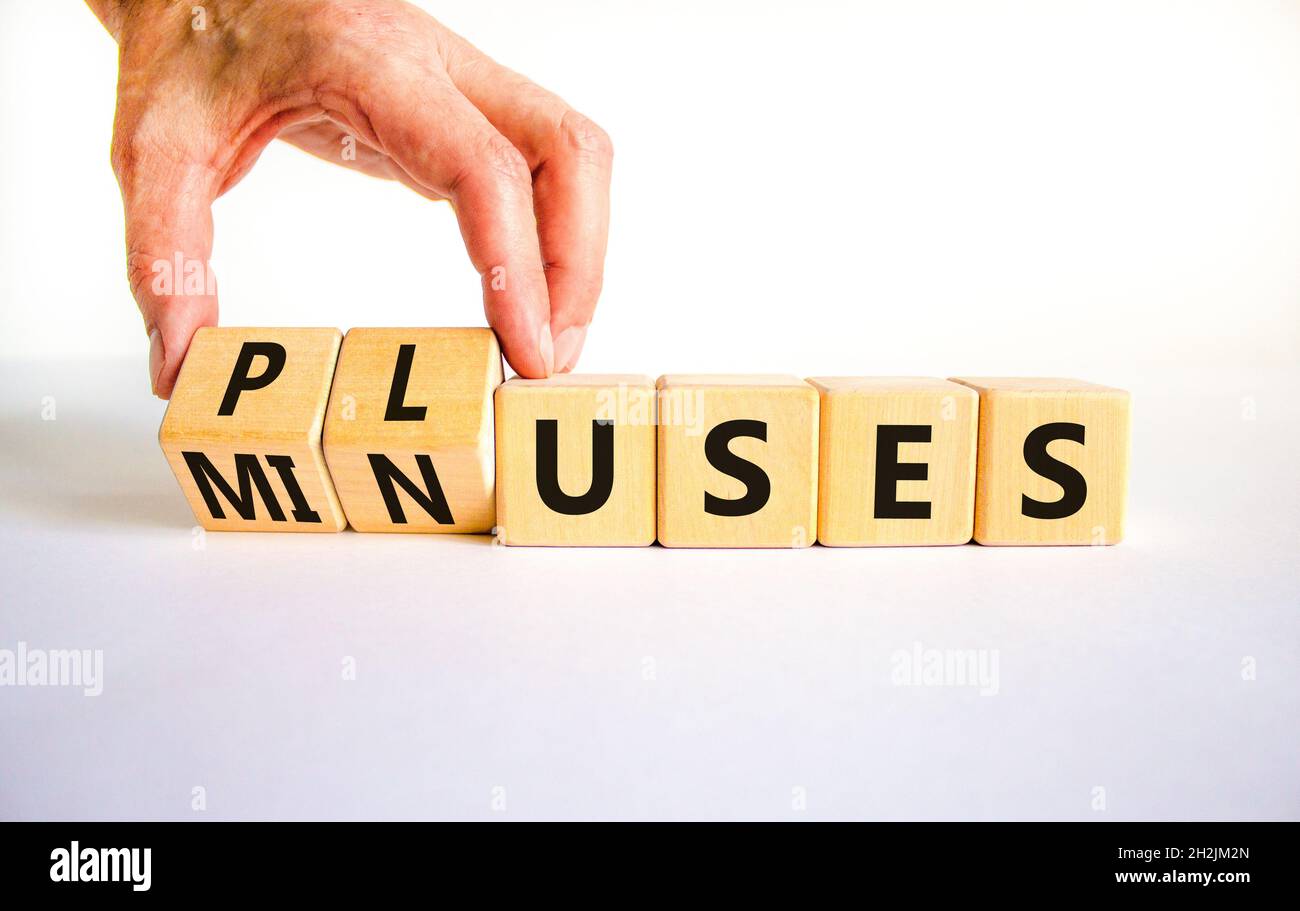 Pluses and minuses symbol. Businessman turns wooden cubes and changes ...