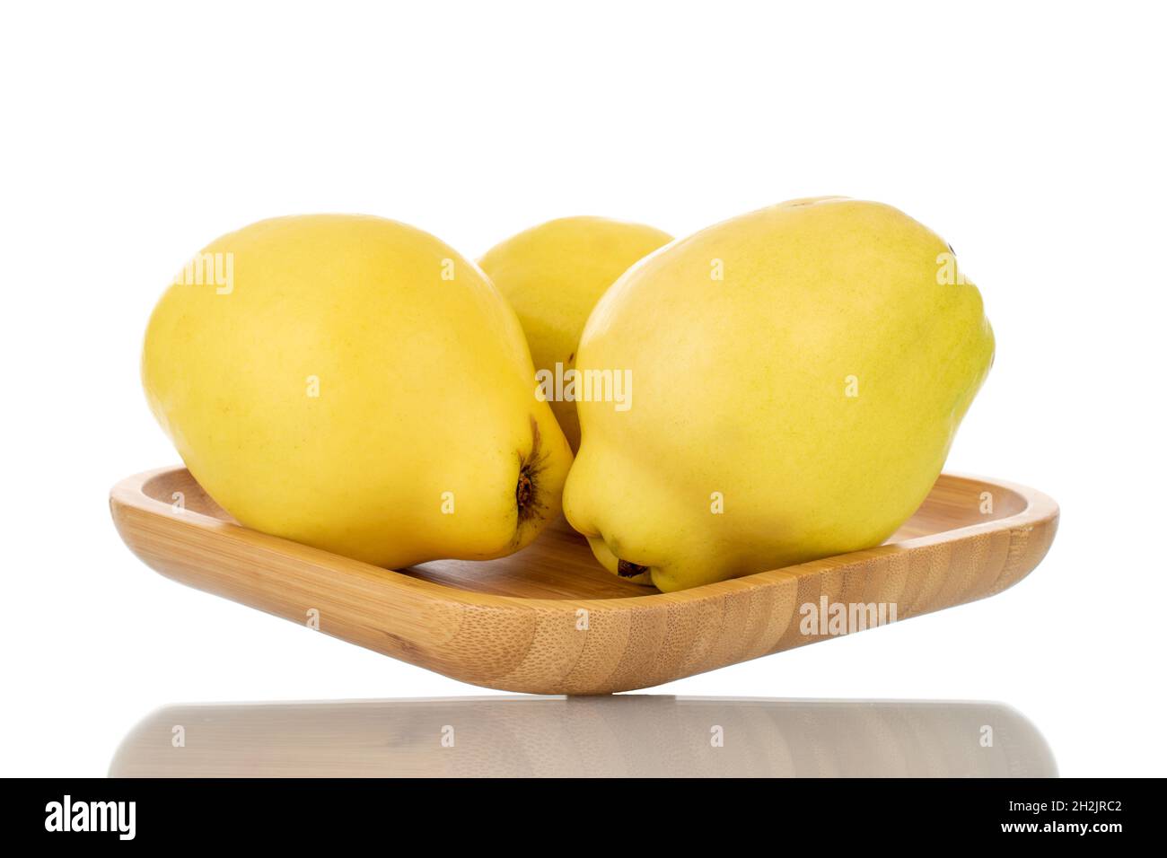 Three ripe bright yellow quince with a tray of wood, close-up, isolated ...