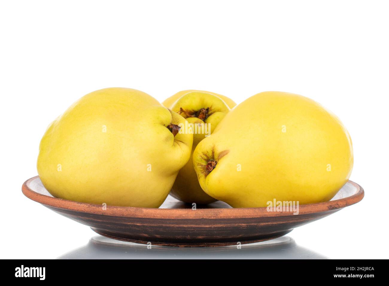 Three ripe bright yellow quince with ceramic dishes, close-up, isolated ...
