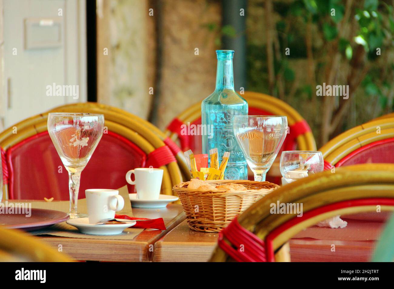 Shot of an outdoor restaurant table with cups, glasses, and a bottle ...
