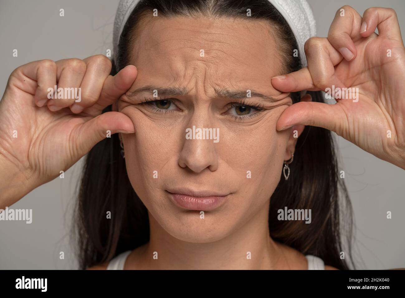 portrait of a young sad woman pinching her wrinkles next to her eyes on ...