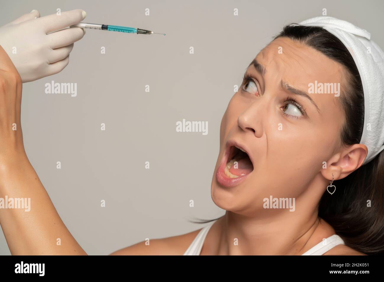 Portrait of a young scared woman on a face filler injection procedure ...