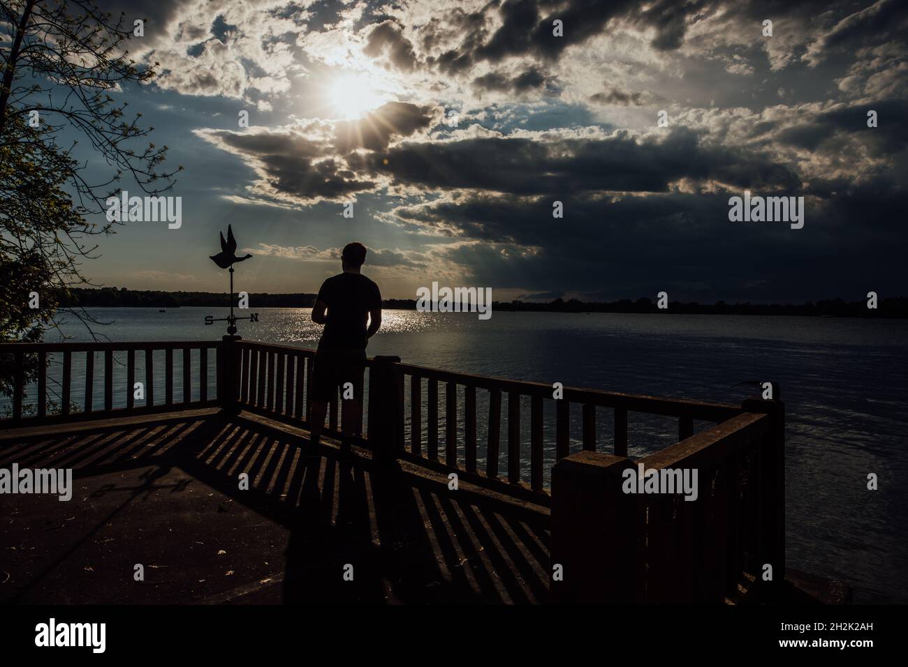 Man on deck at sunset over lake thinking Stock Photo - Alamy
