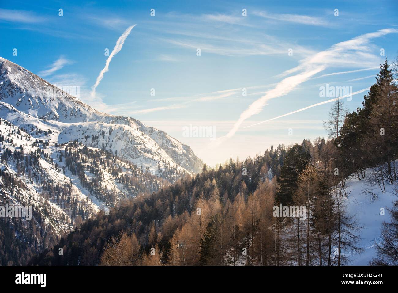 Beautiful sunrise in the Alps. Snow covered mountains and light fog ...