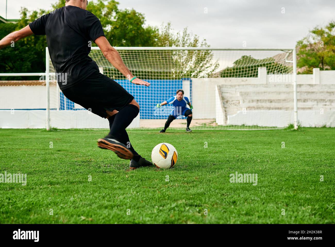 Soccer player shoots a penalty against a goalkeeper on a soccer field ...