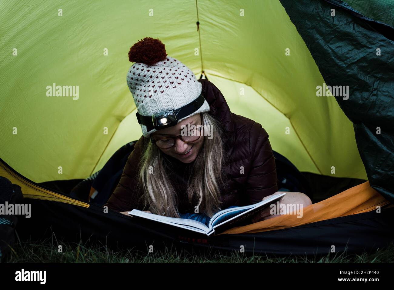 woman happily reading in her tent whilst camping Stock Photo - Alamy