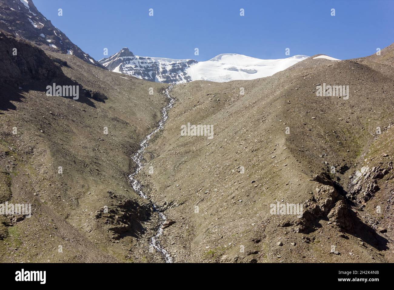 A mountain stream trickling down the rock slope of a Himalayan peak ...