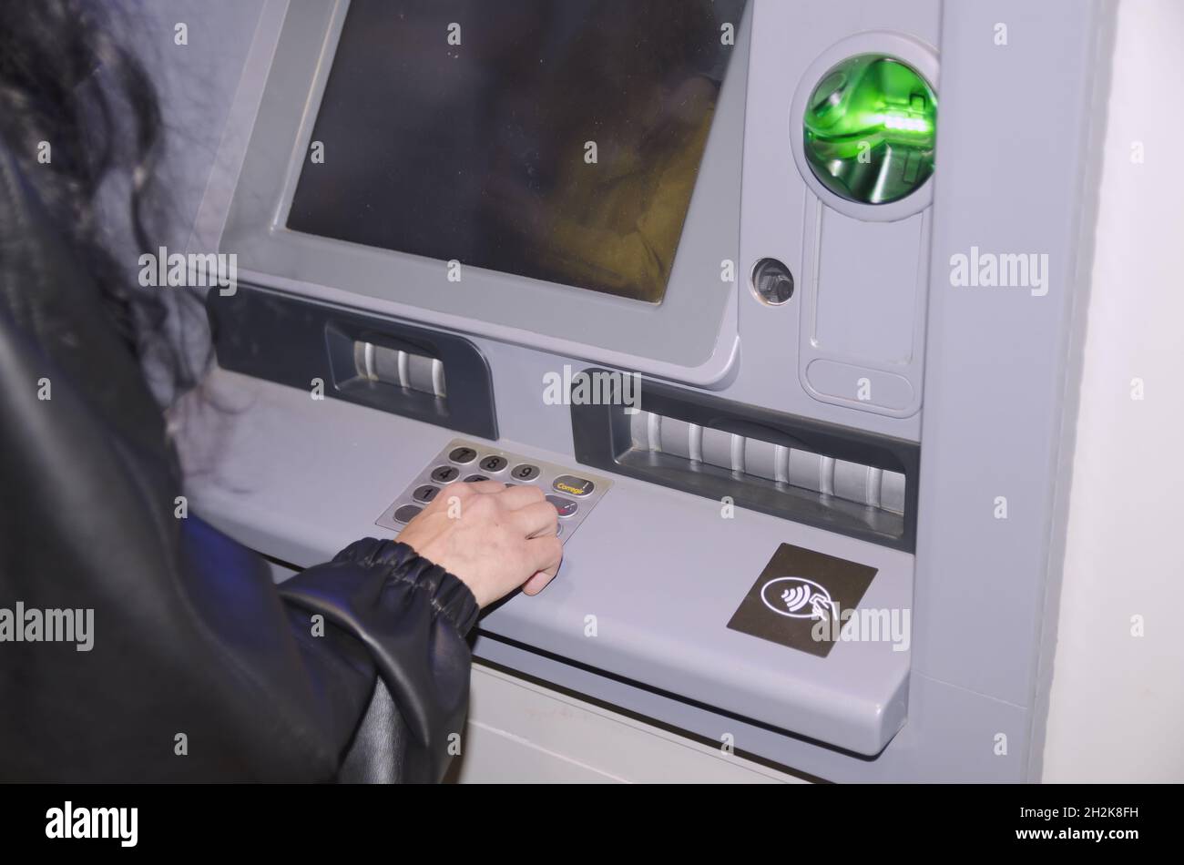 Person using an ATM machine to take out money from her credit card ...