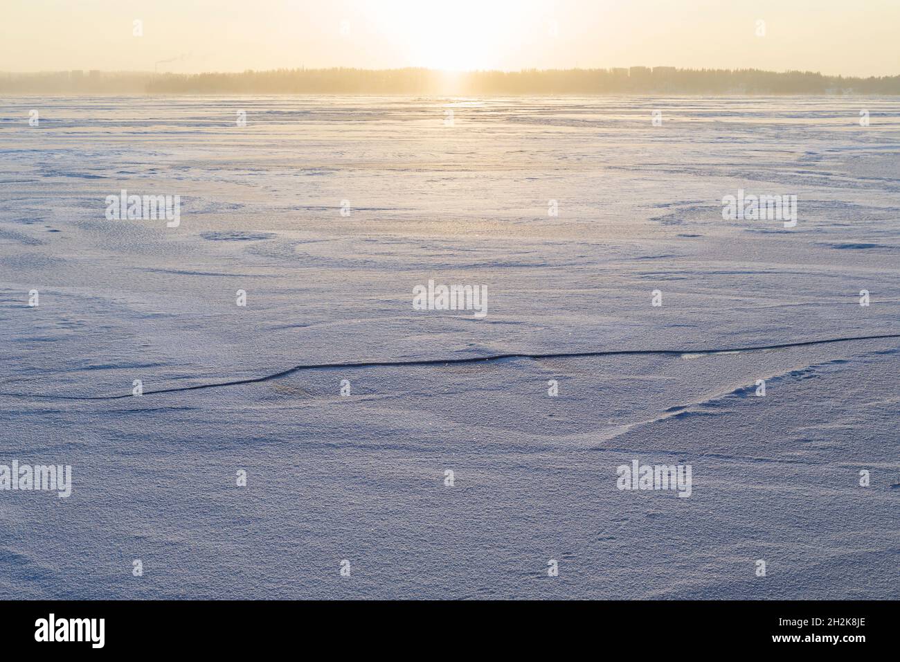 Sun shining above a frozen and snowy lake in Finland in the winter ...