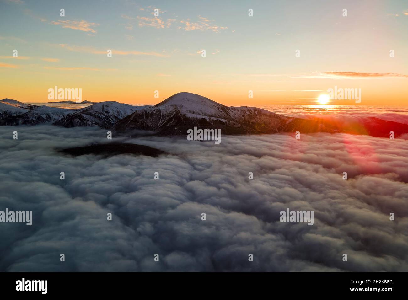 Aerial view of vibrant sunrise over white dense clouds with distant ...