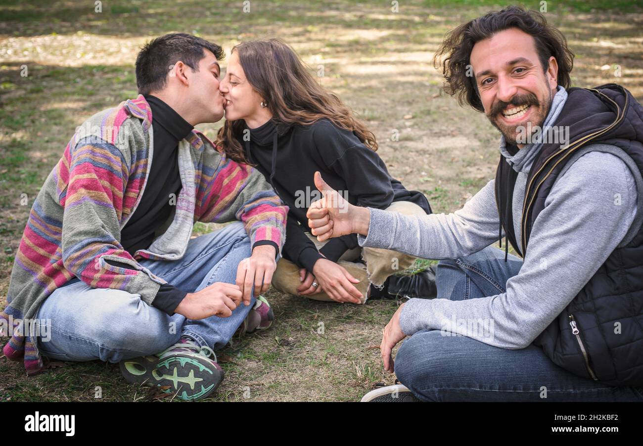 Group of three relaxed and smiling friends, two men and a girl, make ...