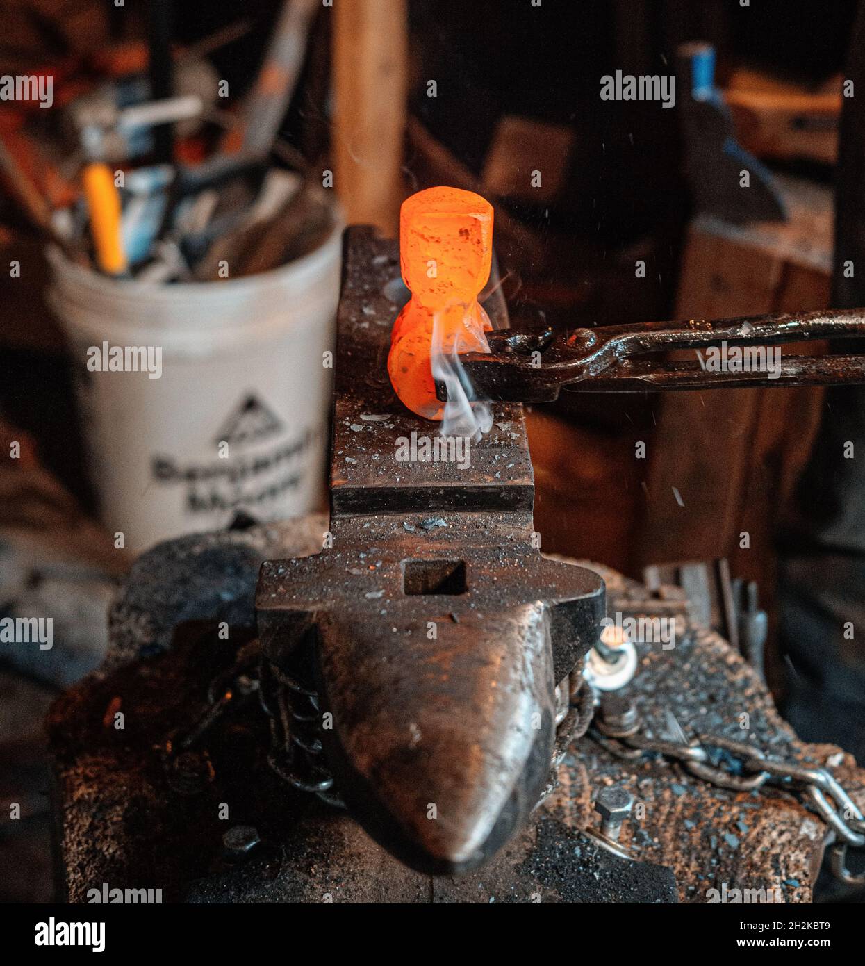 Closeup of forging a small piece of metal in the workshop with a blurry ...