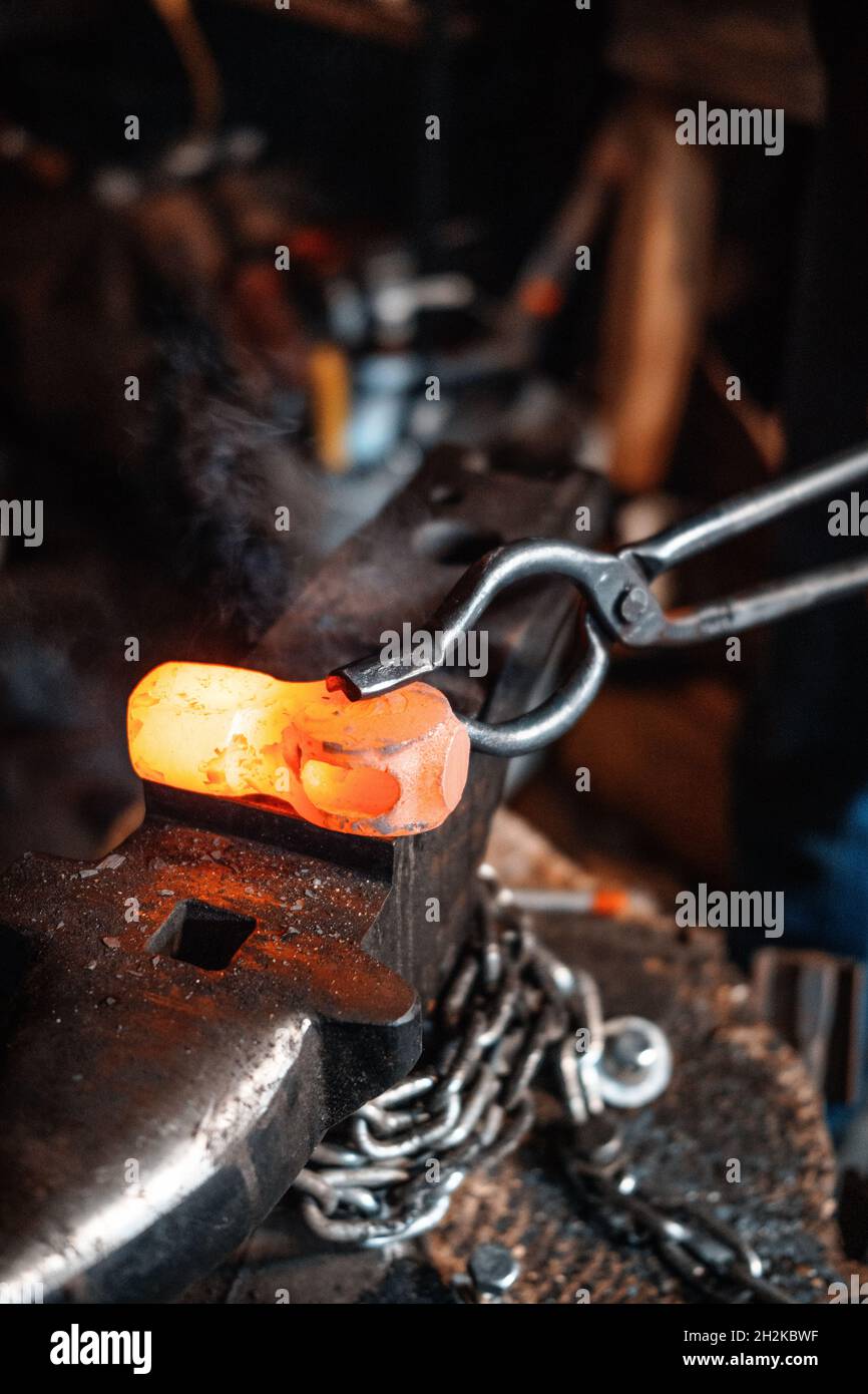 Vertical shot of forging a small piece of metal in the workshop with a ...