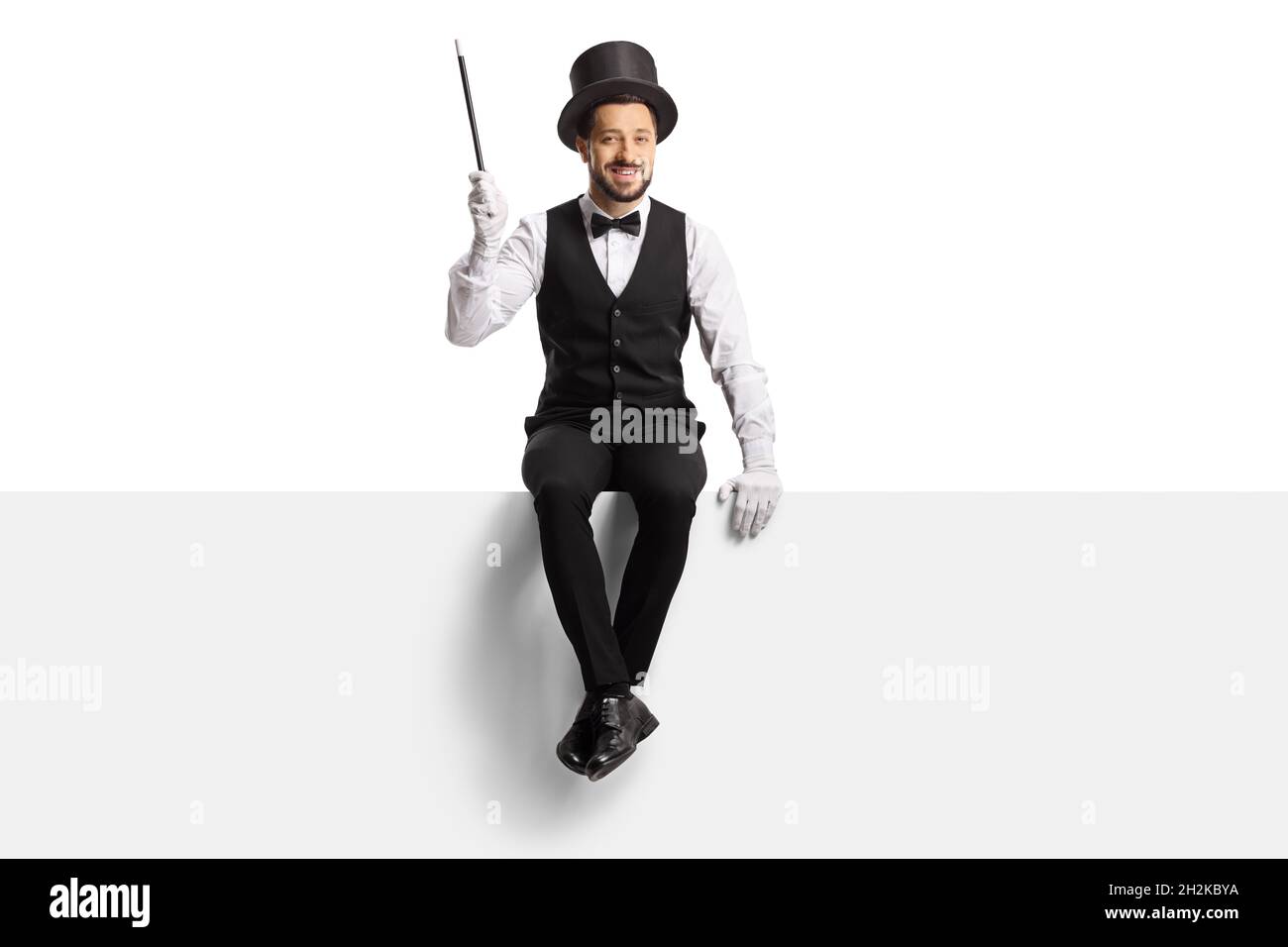 Magician sitting on a blank panel and holding a magic wand isolated on ...