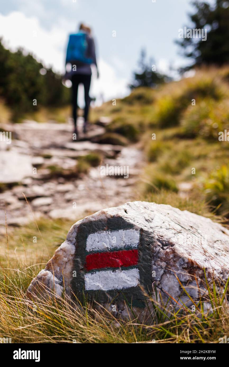 Trail marker. Hiking sign on rock in mountains. Unrecognizable tourist ...