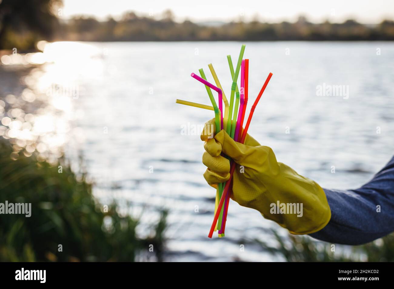 Disposable plastic straw in hand. Water pollution. Global environmental ...