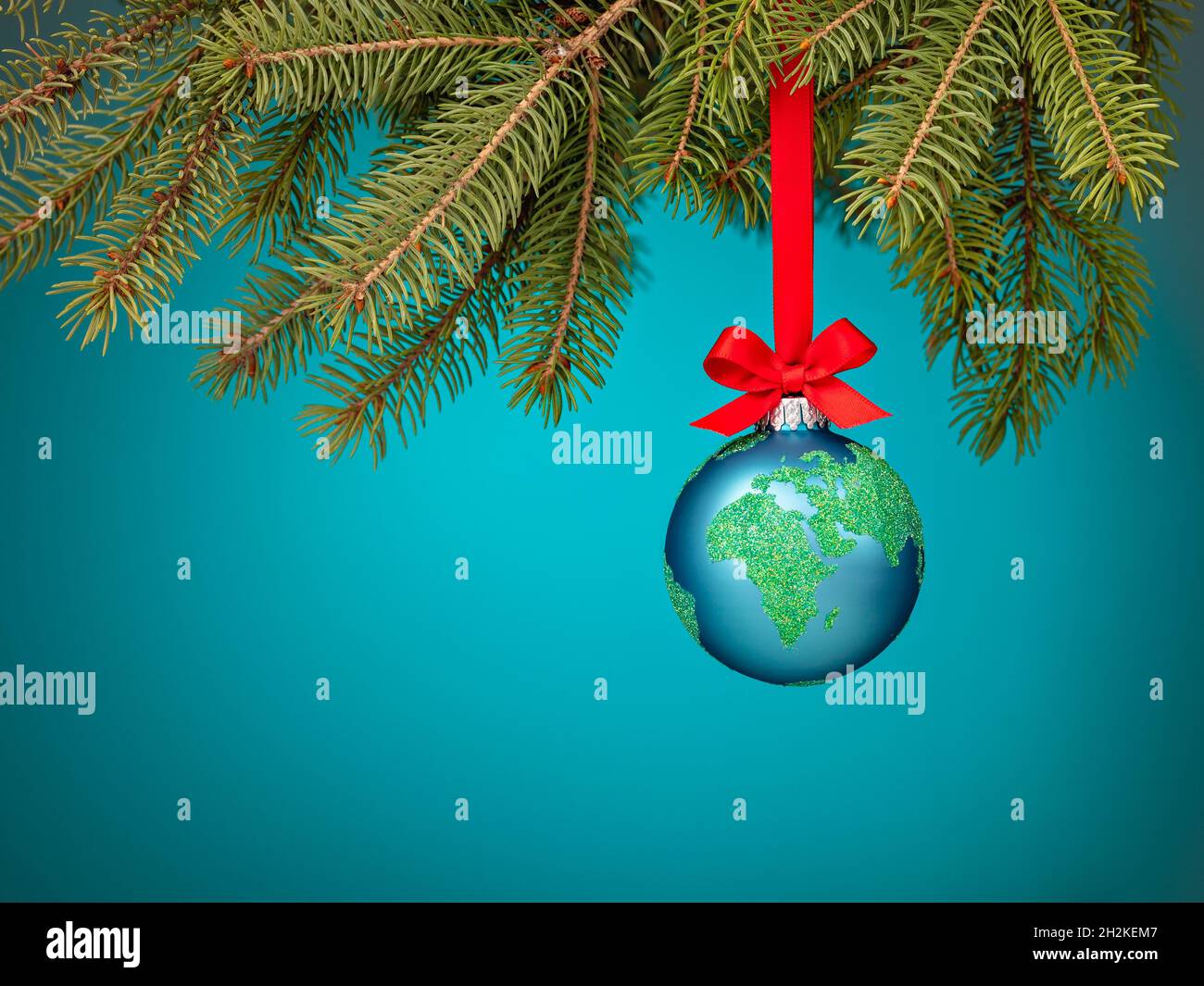 Globe christmas ornament hanging from a tree branch on a blue ...