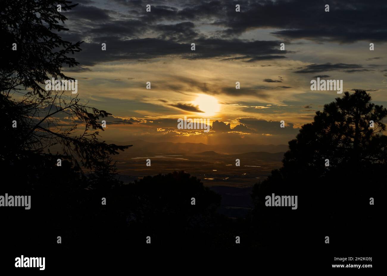 sun setting over the horizon at dusk with a dramatic sky of intense ...