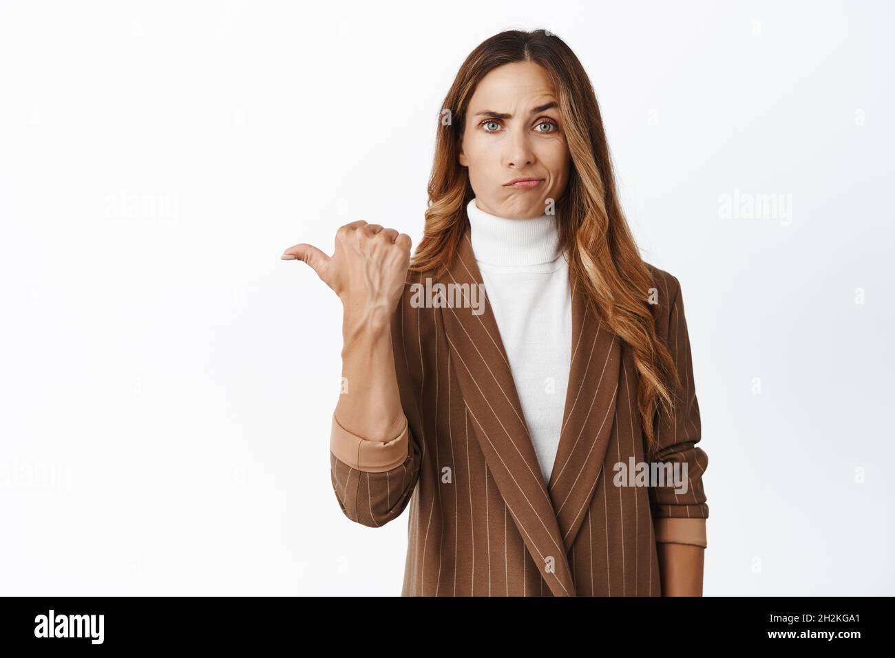 Strict lady boss looking suspicious, pointing left and staring with ...