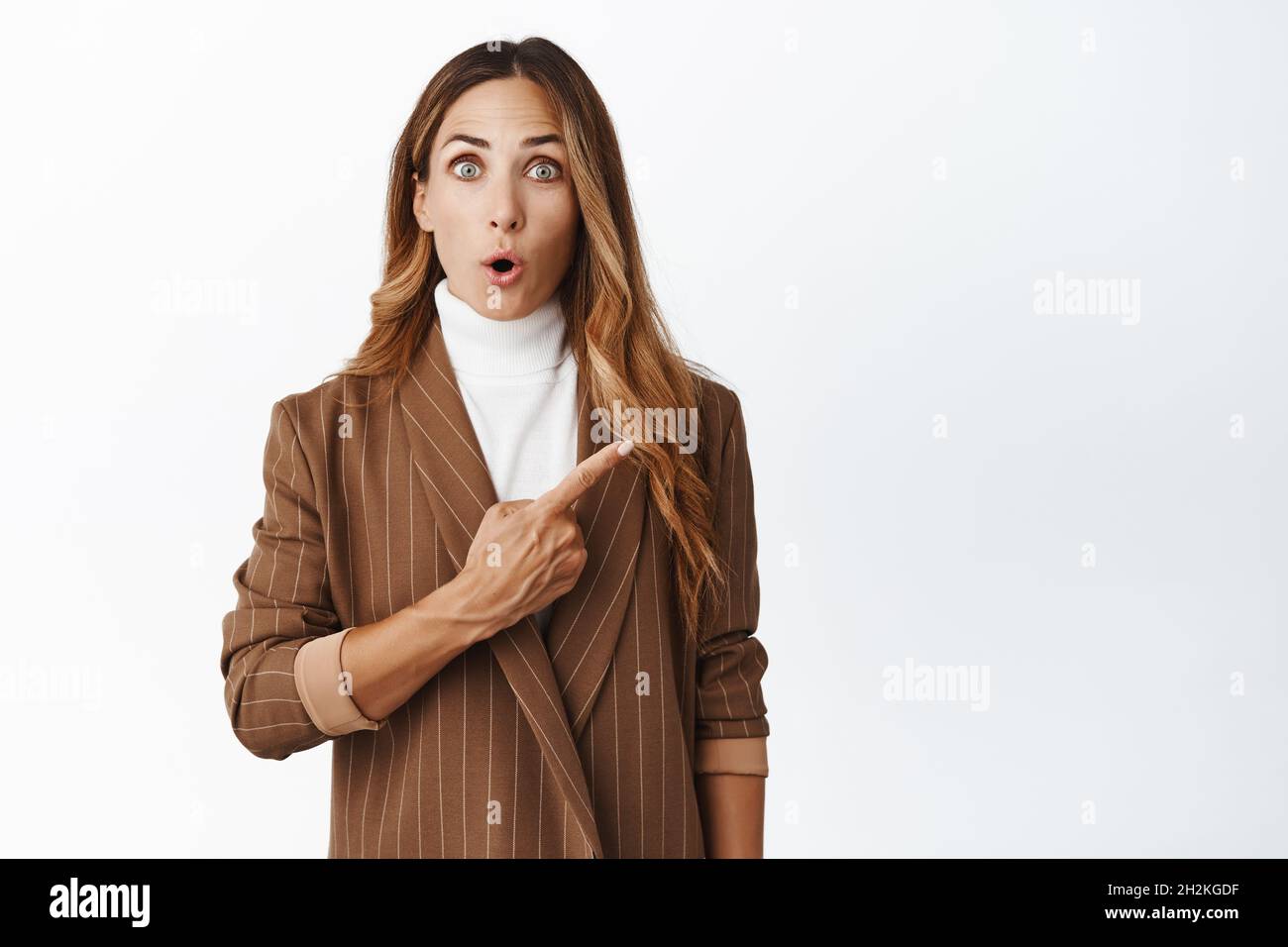 Portrait of surprised businesswoman gasping fascinated, pointing at ...