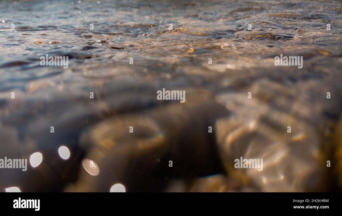 Pebbles stone underwater below water surface near lake shore, natural ...