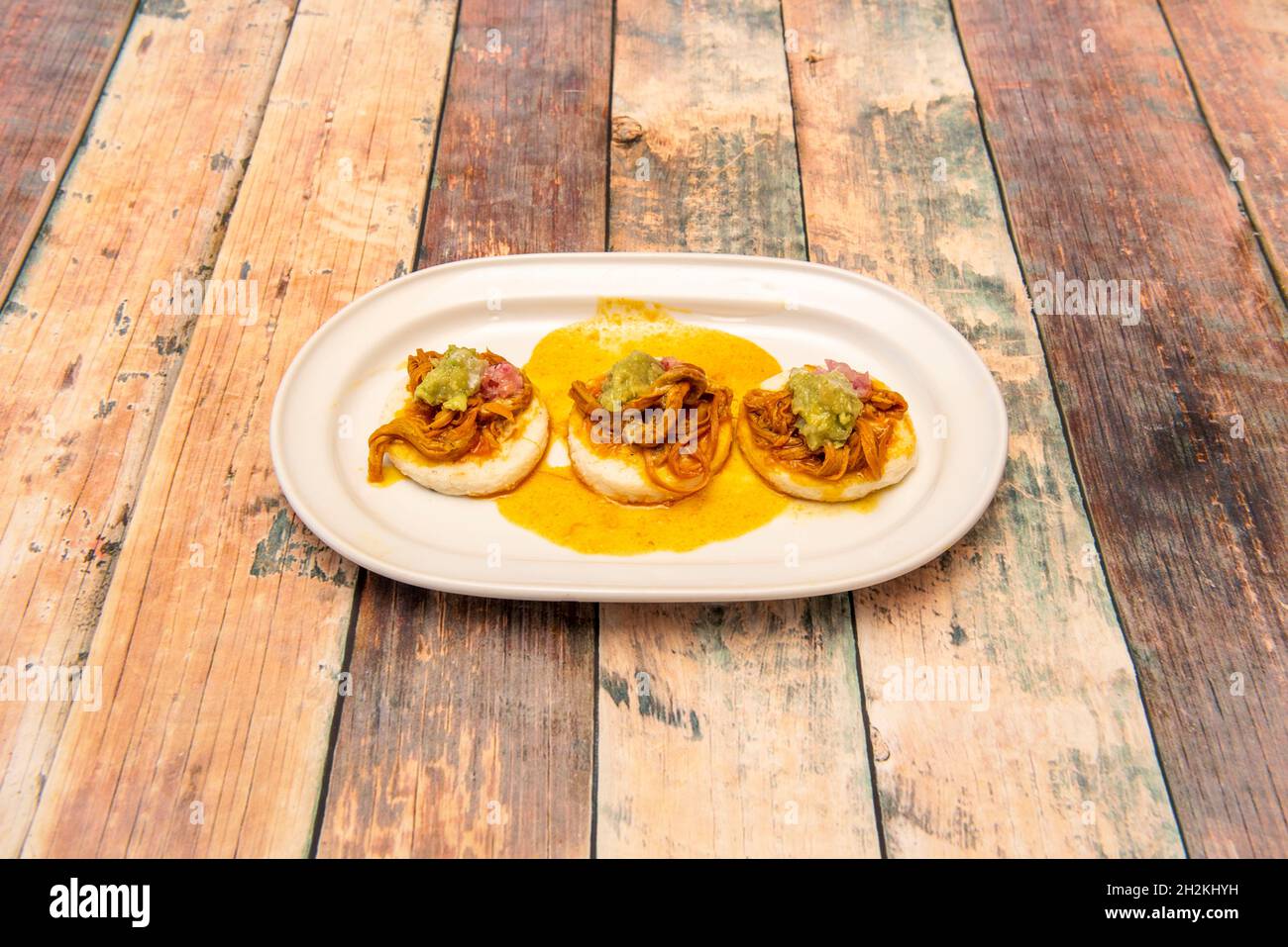 Small Colombian corn flour arepas with shredded meat, purple onion and ...