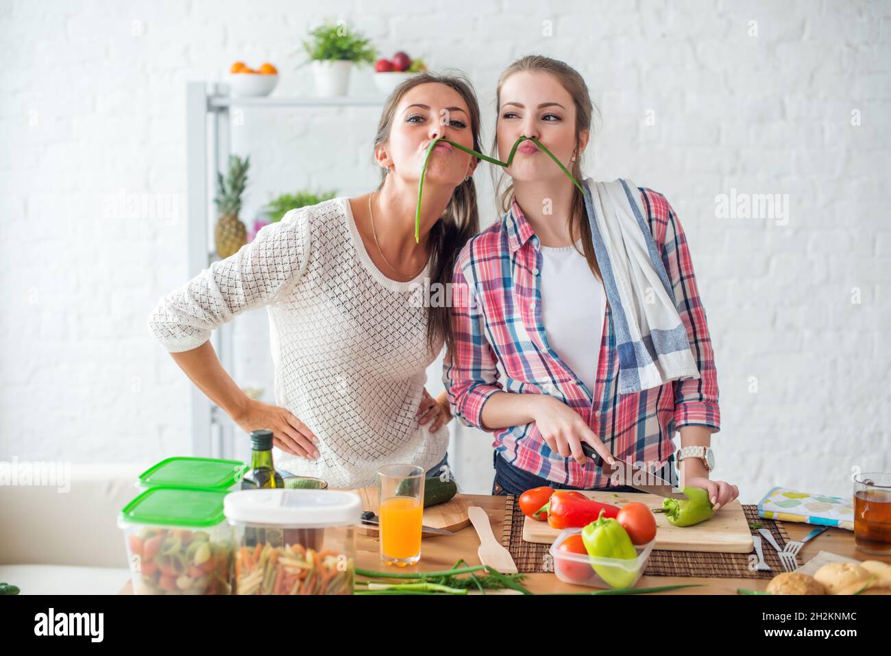 Women preparing healthy food playing with vegetables in kitchen having ...