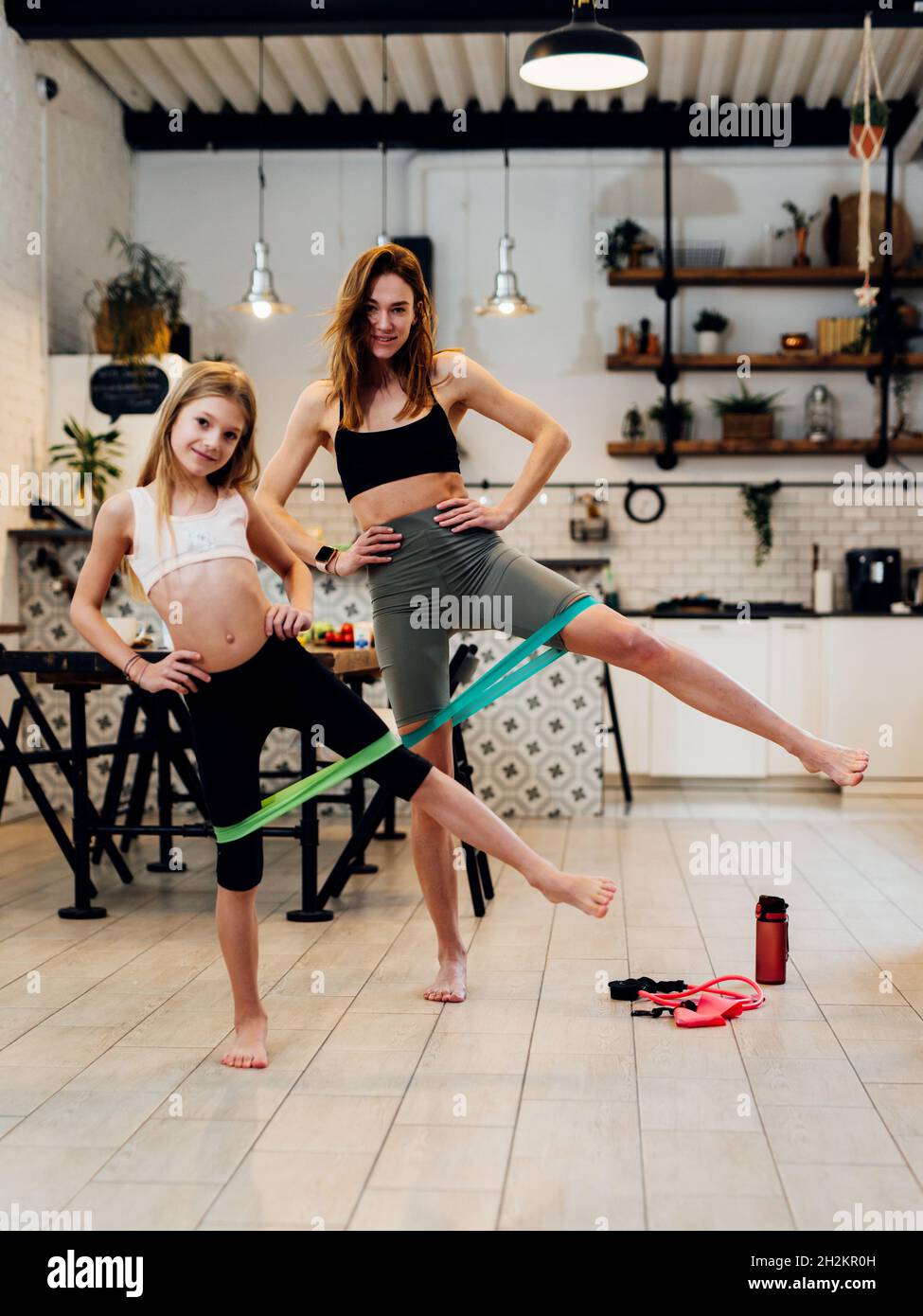 Mother And Daughter Working Out At Home Doing Resistance Band Leg