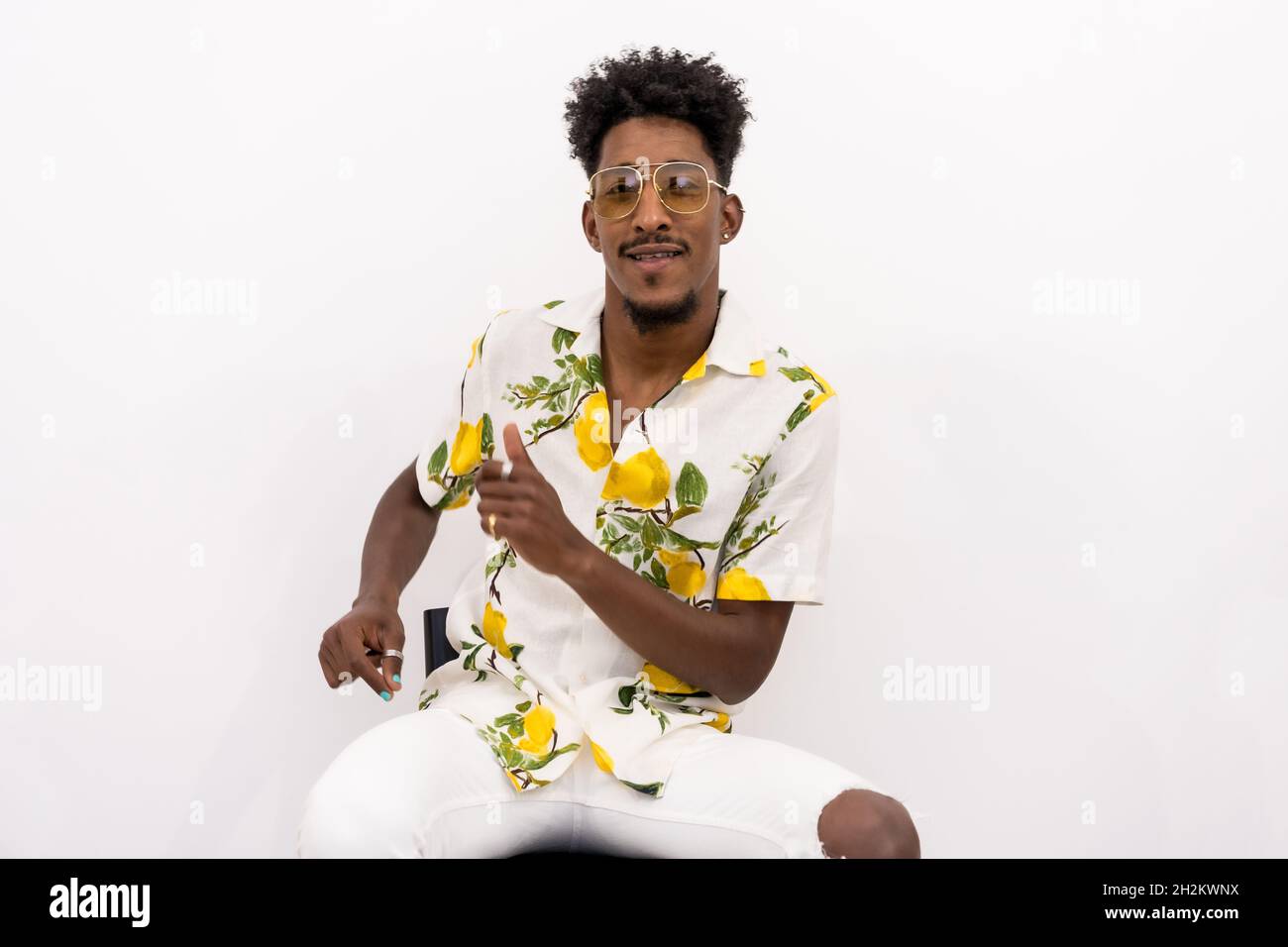 Young Cuban male in a floral shirt and sunglasses smiling and dancing ...