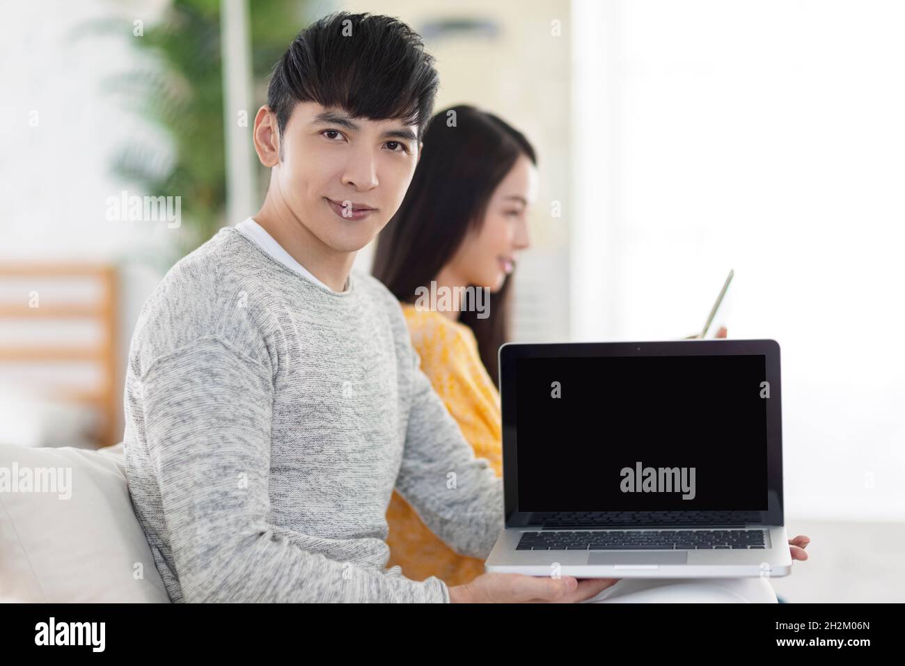 Young couple using computer together in the living room.Showing ...