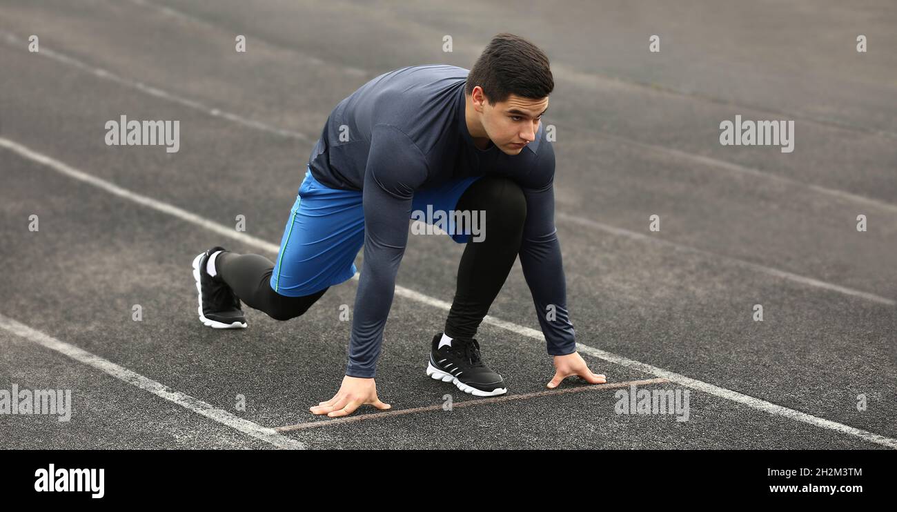 Muscular young man in crouch start position at stadium Stock Photo - Alamy