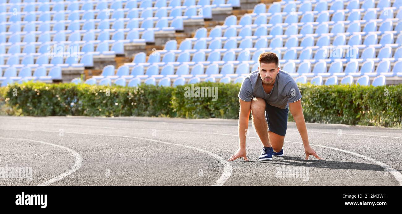 Sporty man in crouch start position at the stadium Stock Photo - Alamy