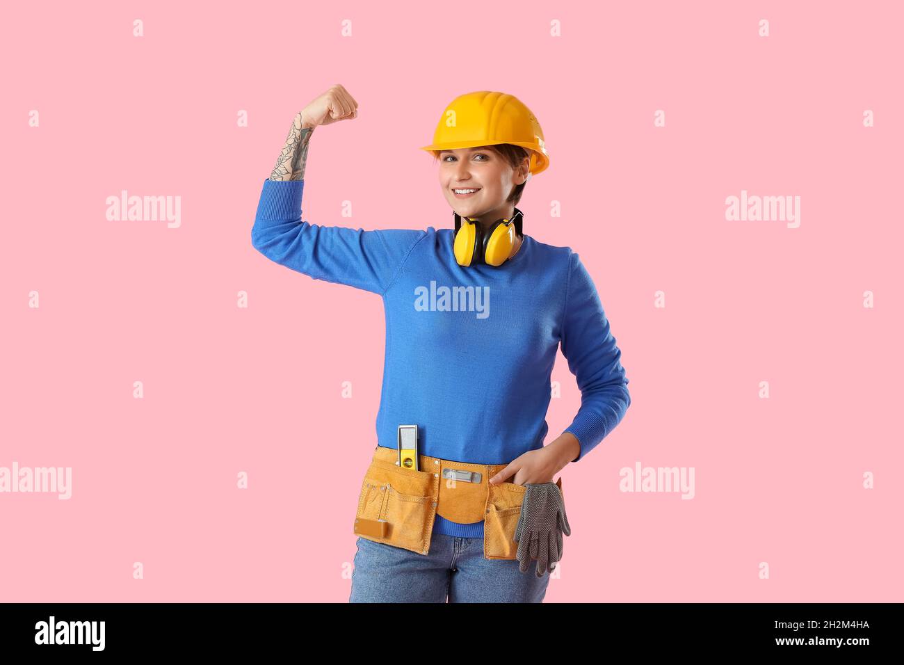 Female construction worker with hardhat and ear protectors on pink ...