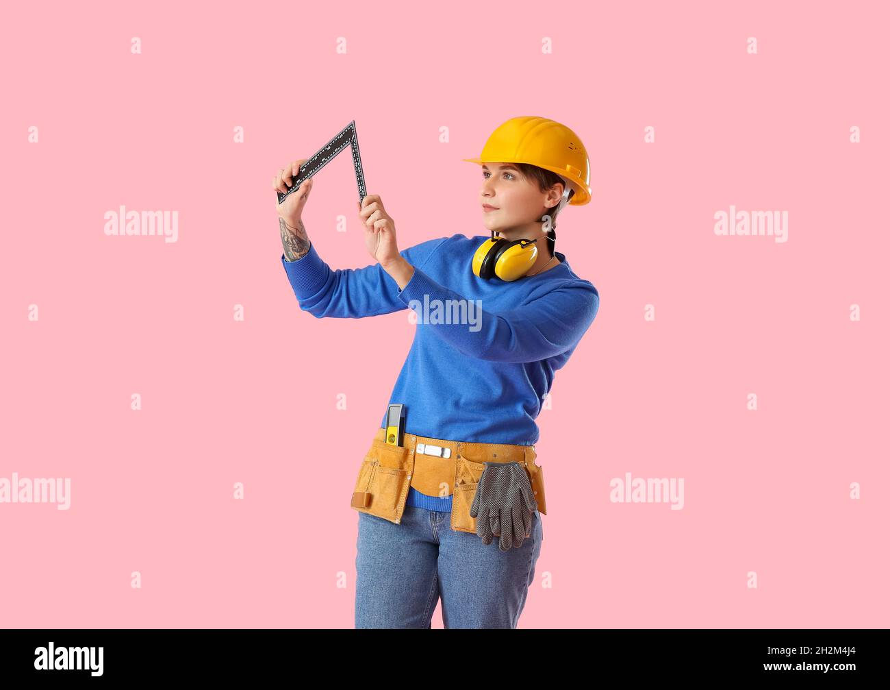 Female construction worker with ruler on pink background Stock Photo ...