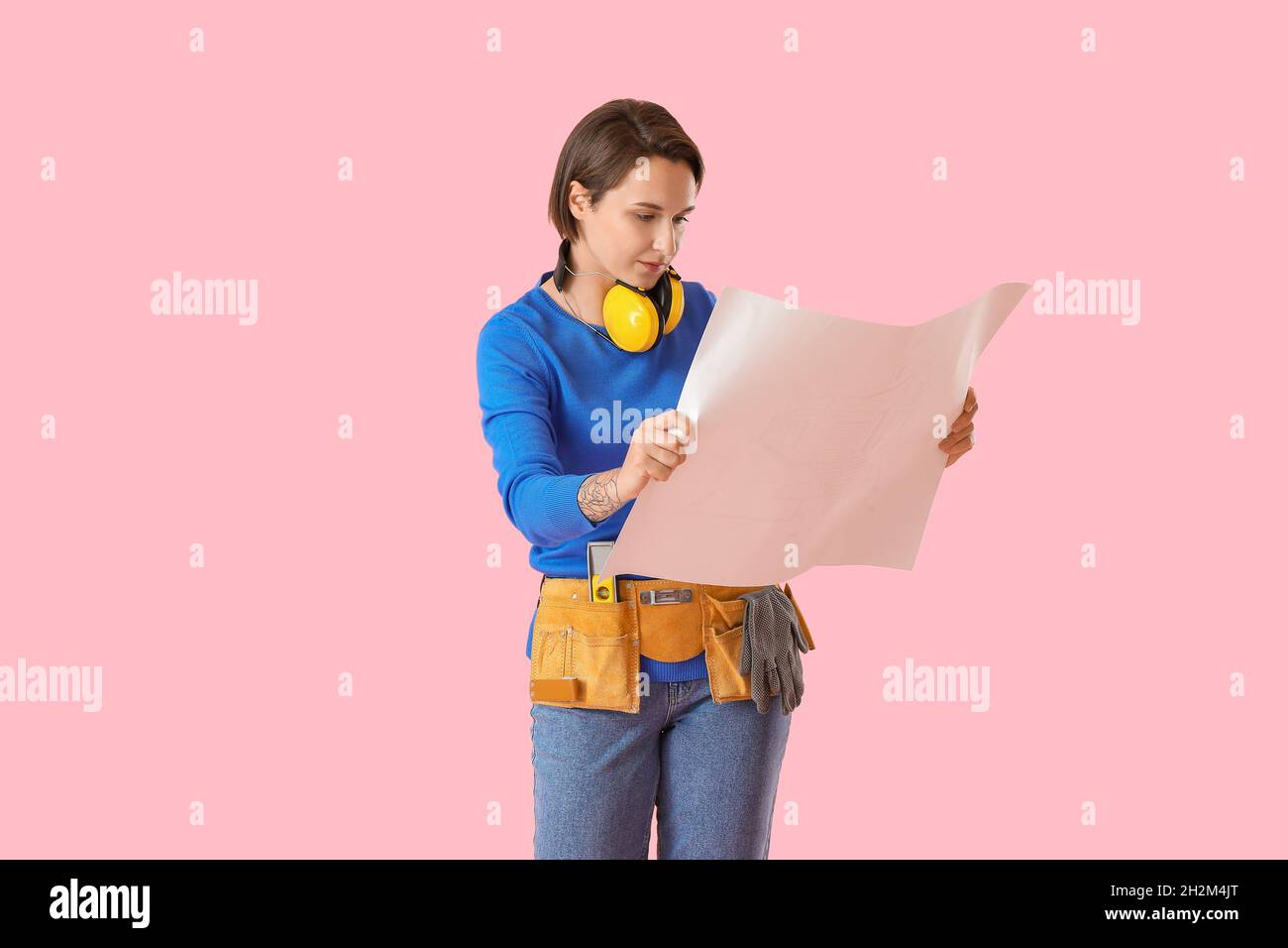 Female construction worker with house plan on pink background Stock ...