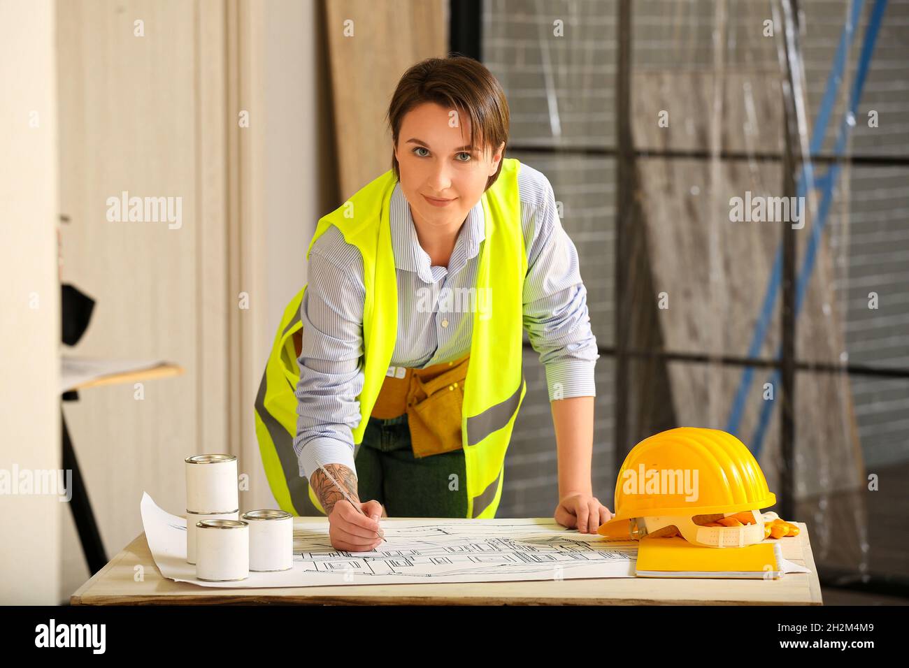 Female construction worker writing on house plan in room Stock Photo ...
