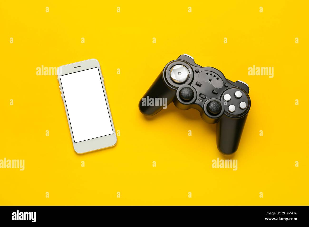 Modern mobile phone and joystick on yellow background Stock Photo - Alamy