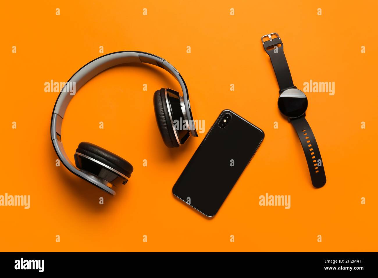 Modern headphones, mobile phone and smart watch on orange background ...