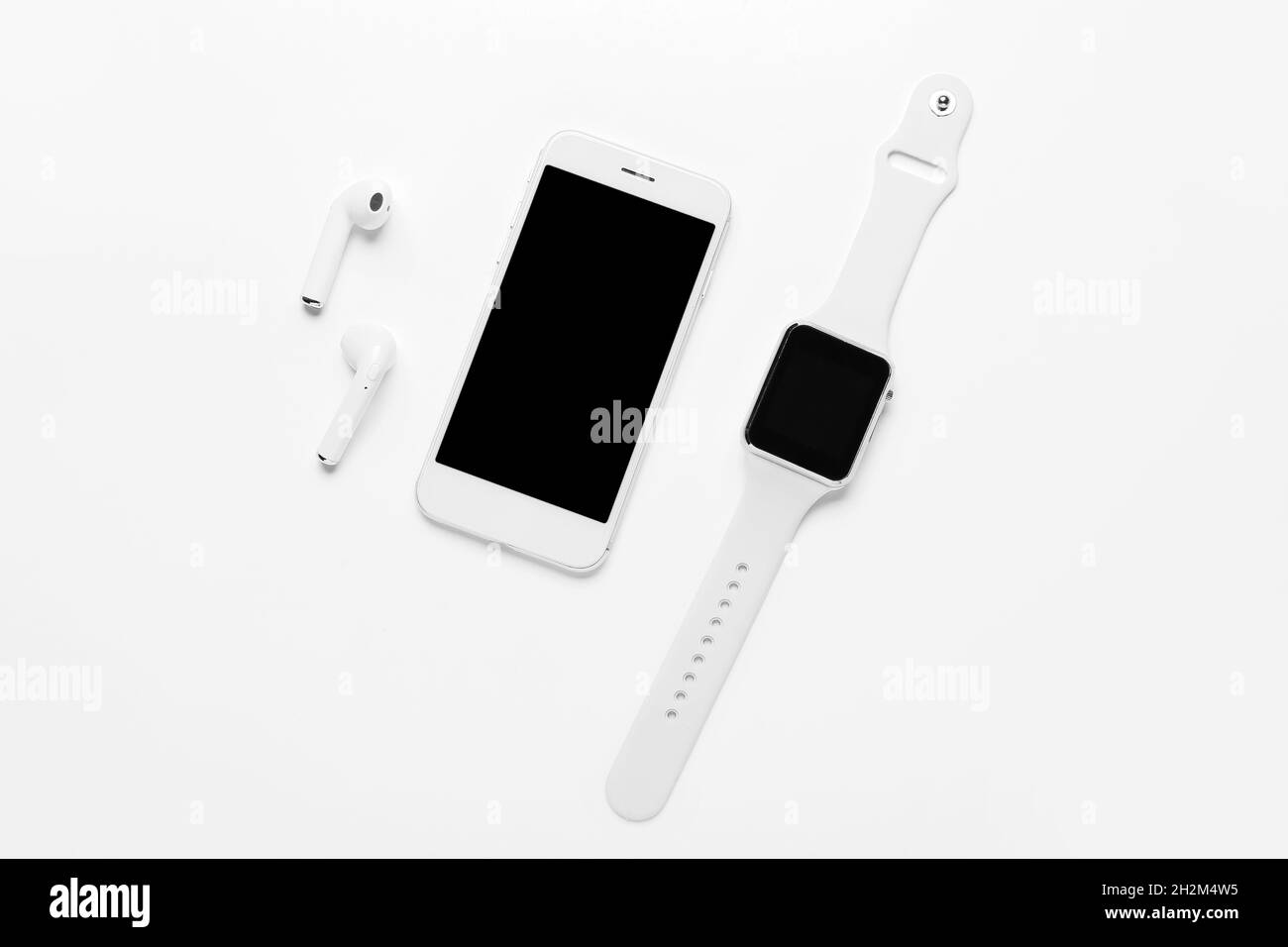 Modern earphones, mobile phone and smart watch on white background ...
