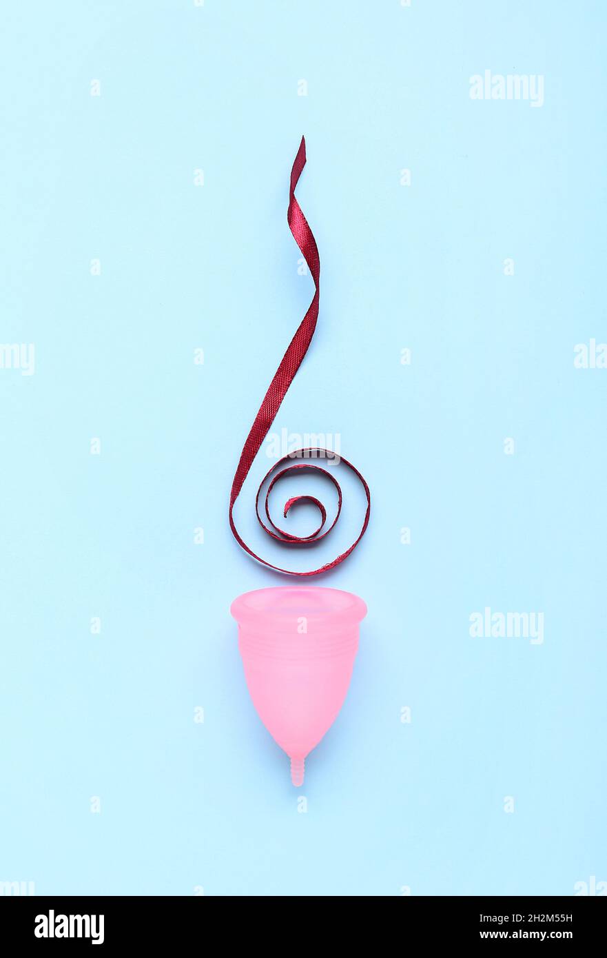 Menstrual cup with ribbon on color background Stock Photo - Alamy