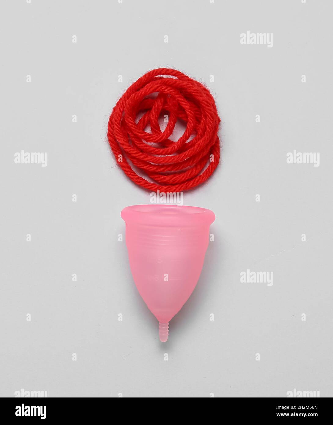 Menstrual cup and thread on grey background Stock Photo - Alamy
