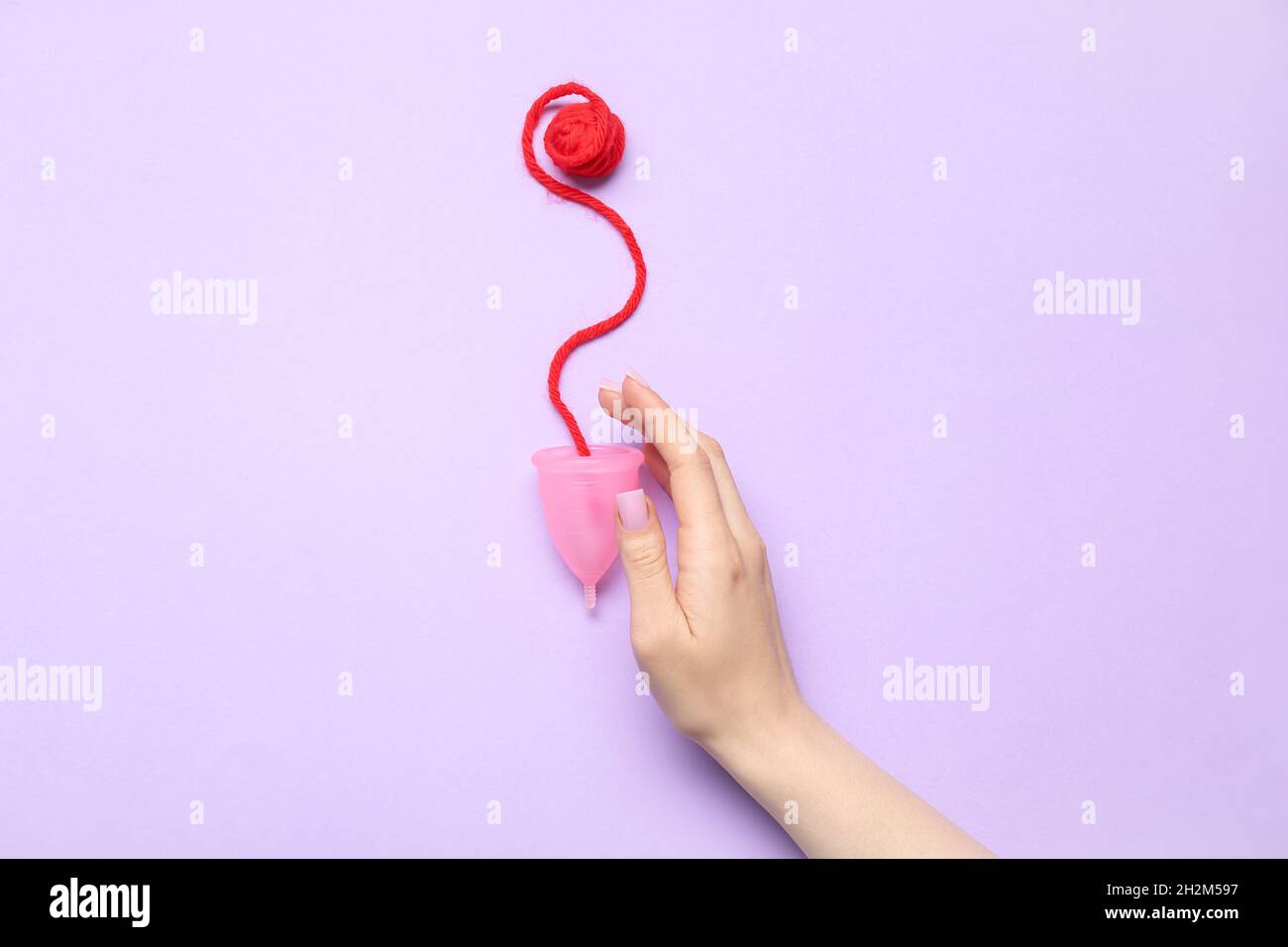 Female hand with menstrual cup and thread on purple background Stock ...