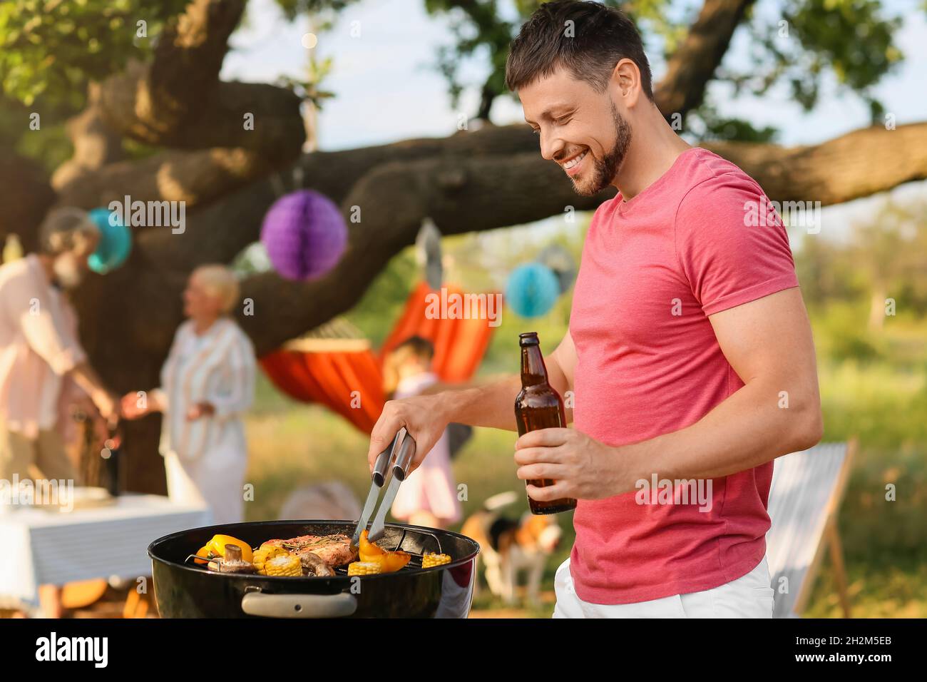 Happy man drinking beer and cooking food at barbecue party on summer ...